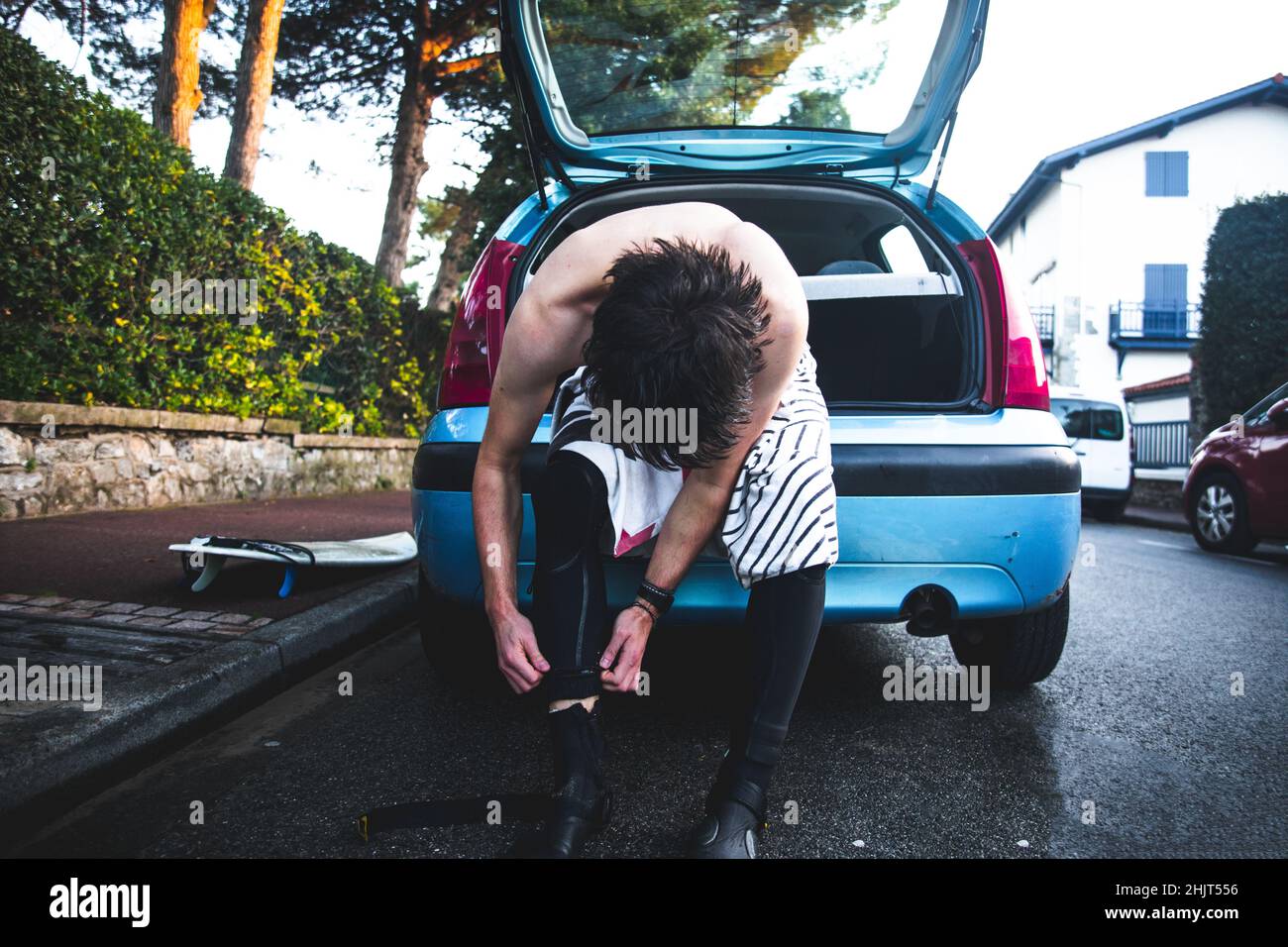 Young caucasian man changing clothes on the car trunk after surfing at ...