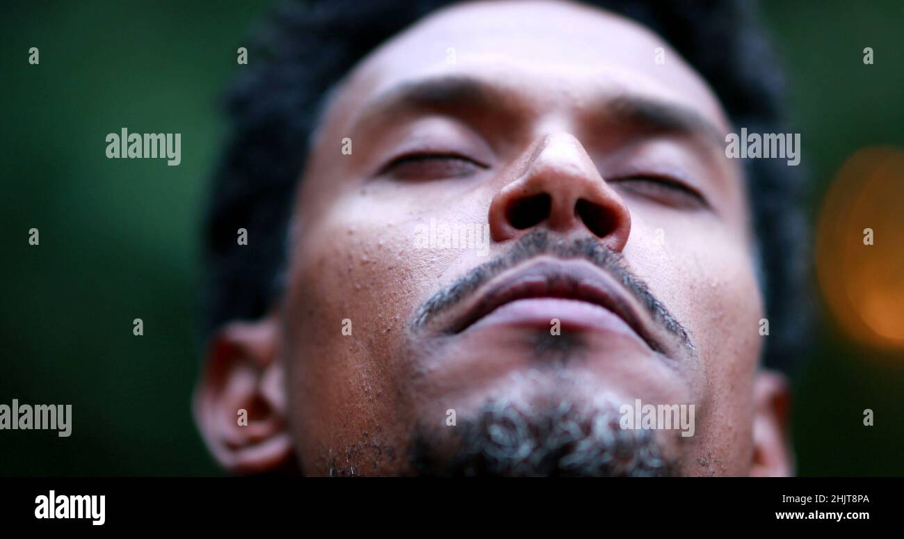 Black man meditating outside taking a deep breath and opening eyes to ...