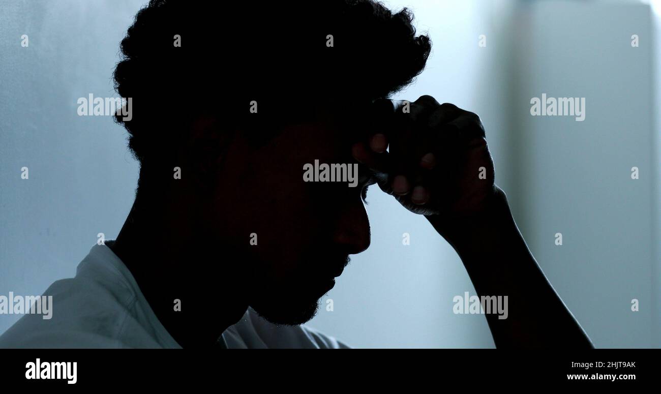 Depressed man sitting on floor. Sad unhappy person holding his forehead ...