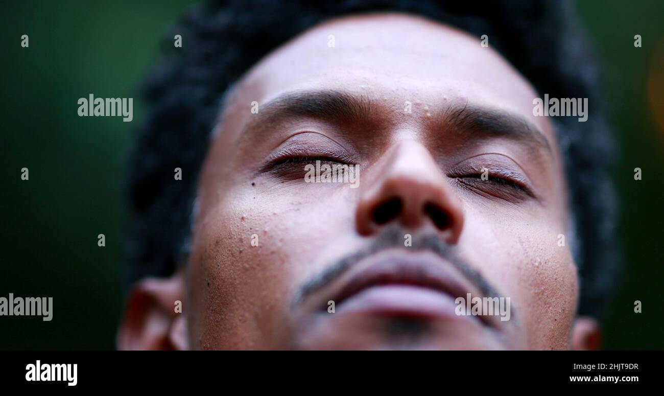 Serene man opening eyes in contemplation looking up to the sky with ...