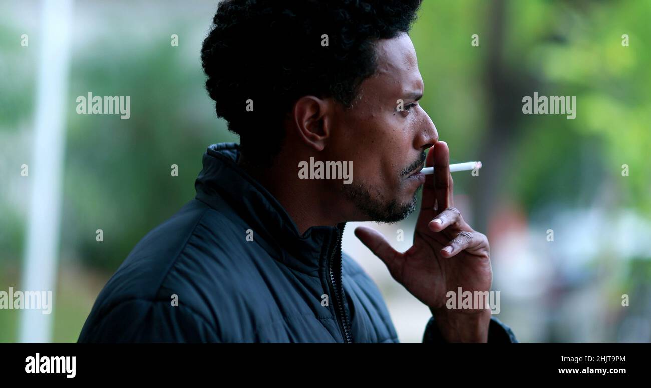 Pensive black african man smoking cigarette outdoors Stock Photo - Alamy