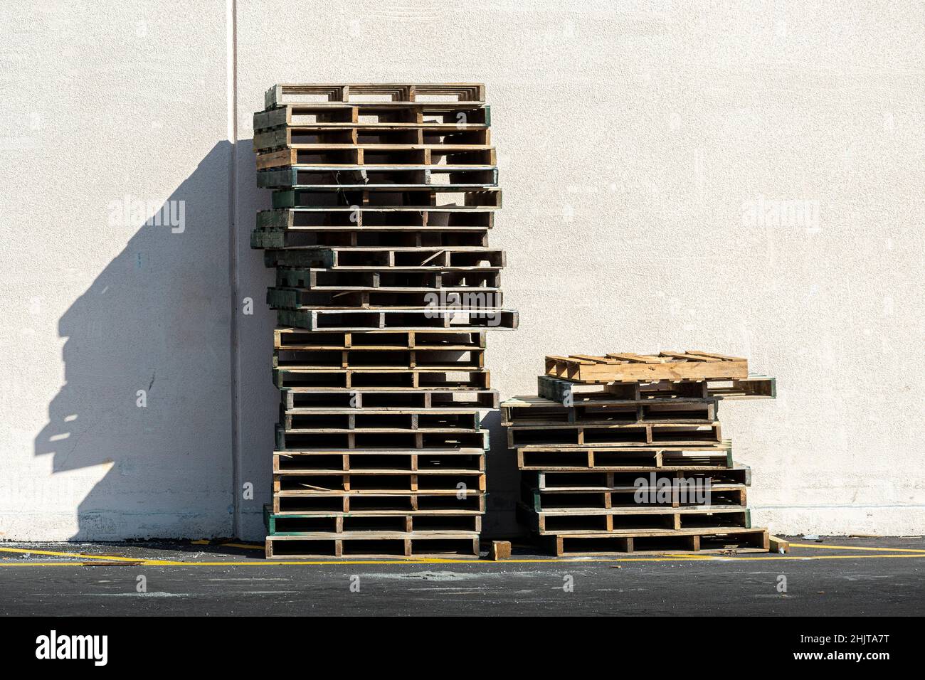 Horizontal shot of a stack of empty wooden pallets against a wall with ...