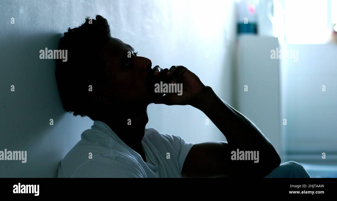 Worried black man sitting on floor feeling preoccupied, person with ...
