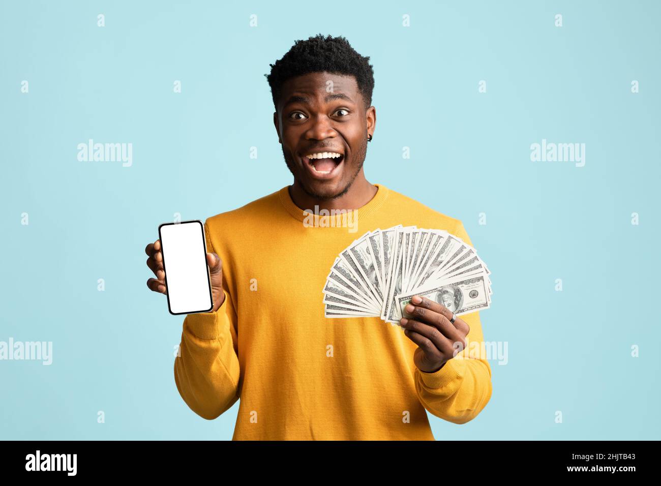Handsome african american young man showing cellphone and cash, mockup ...