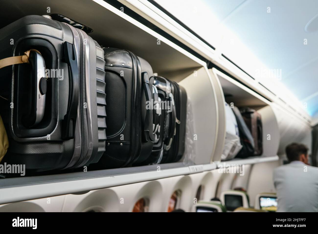 Airplane overhead locker with black plastic baggage suitcases, closeup ...