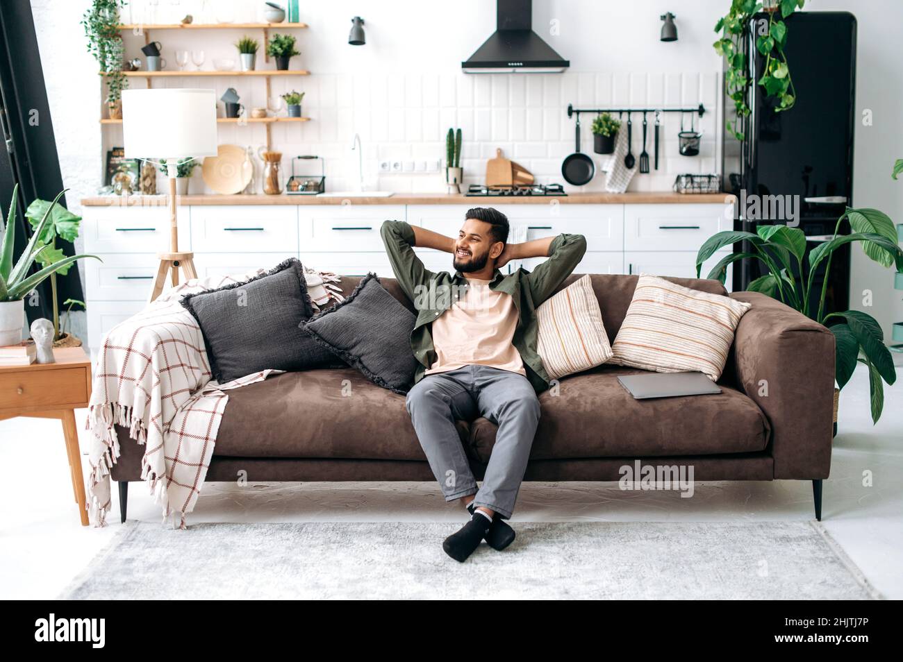 Satisfied relaxed young indian man chilling on sofa in living room ...