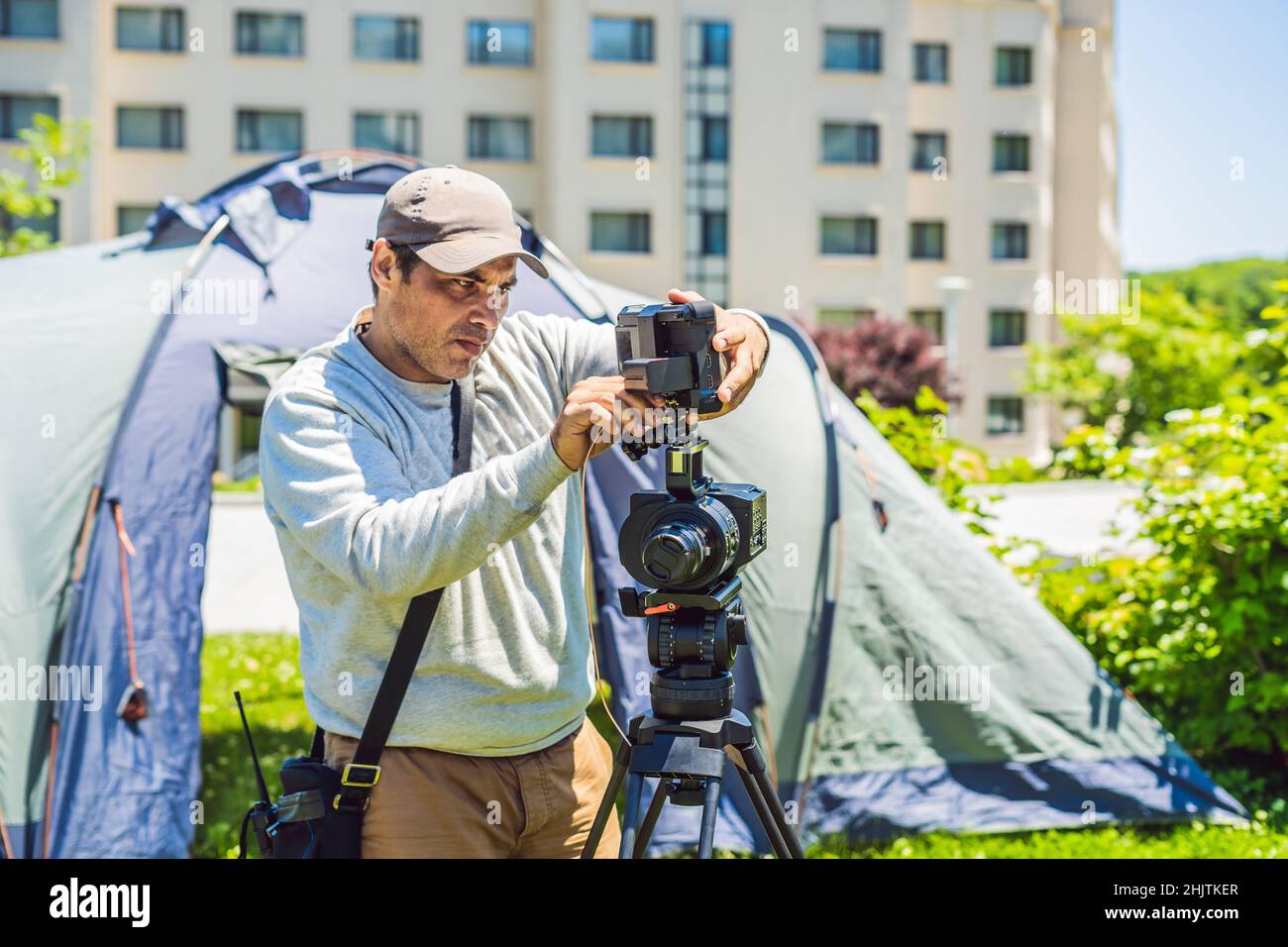a professional cameraman prepares a camera and a tripod before shooting ...