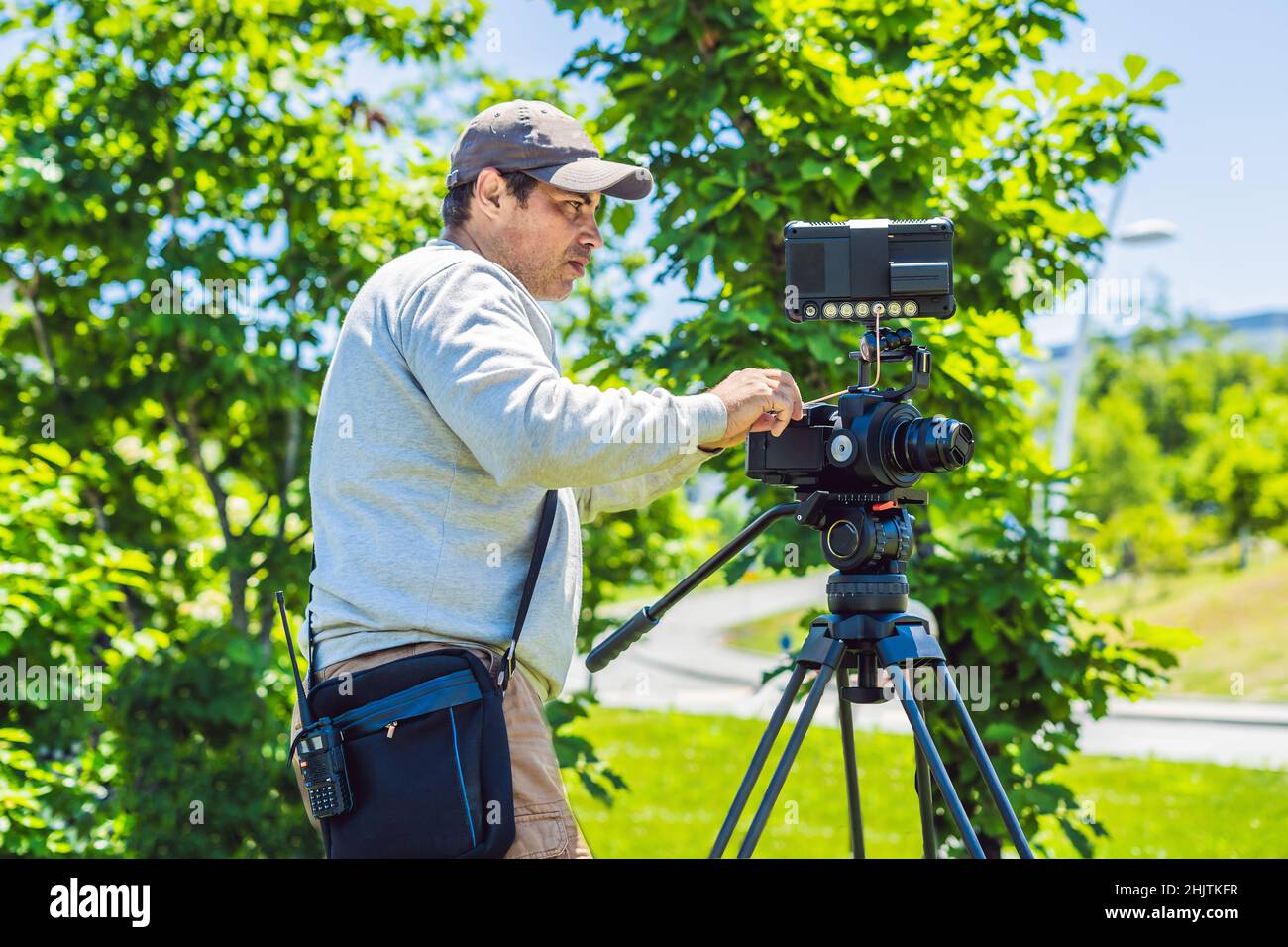 a professional cameraman prepares a camera and a tripod before shooting ...