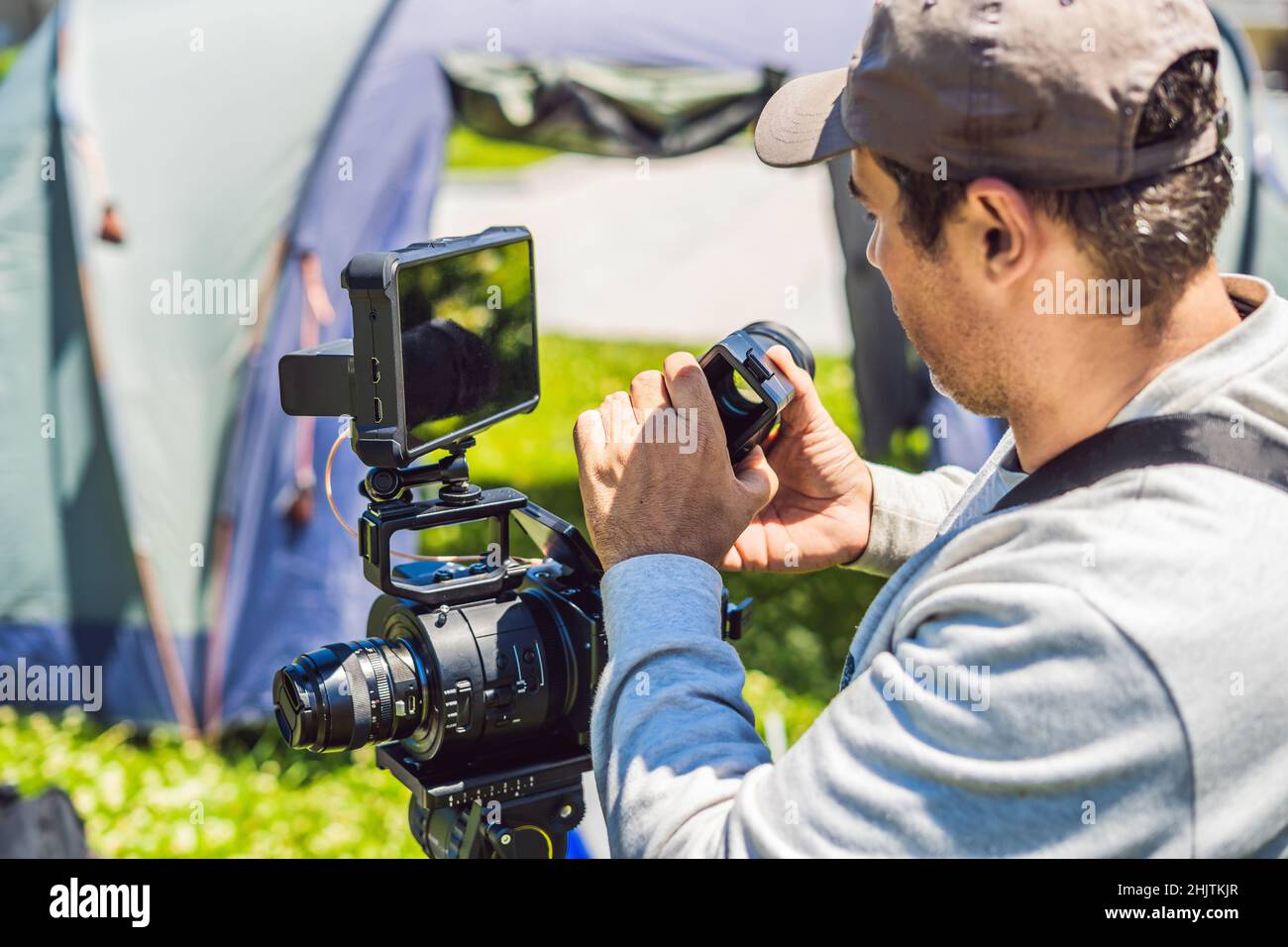 a professional cameraman prepares a camera and a tripod before shooting ...