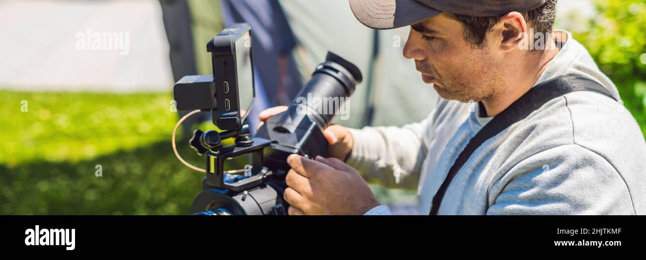a professional cameraman prepares a camera and a tripod before shooting ...