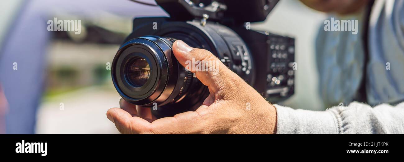 a professional cameraman prepares a camera and a tripod before shooting ...