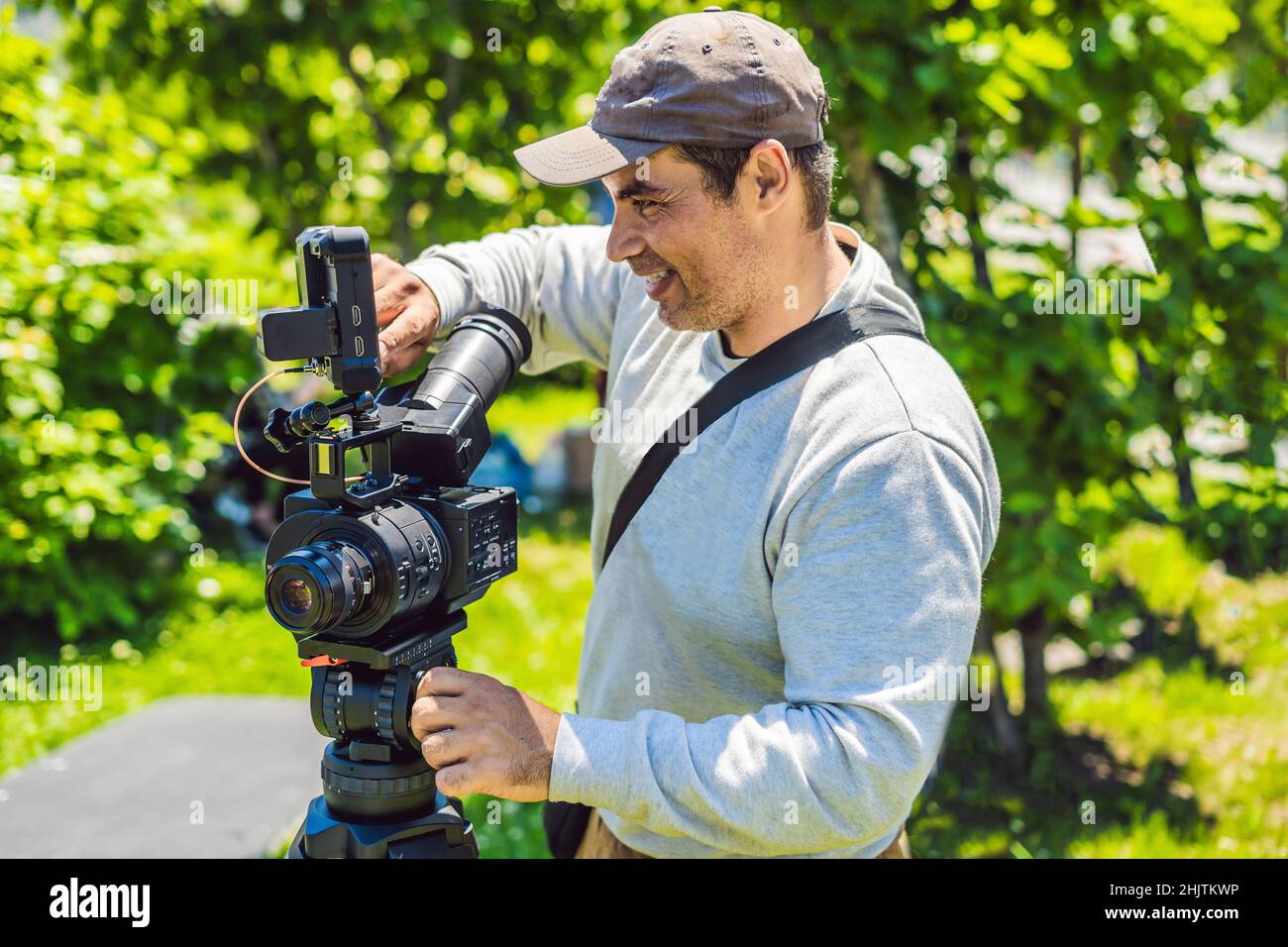 a professional cameraman prepares a camera and a tripod before shooting ...