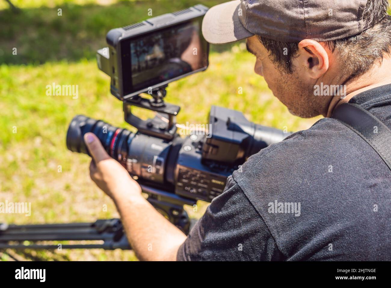 a professional cameraman prepares a camera and a tripod before shooting ...