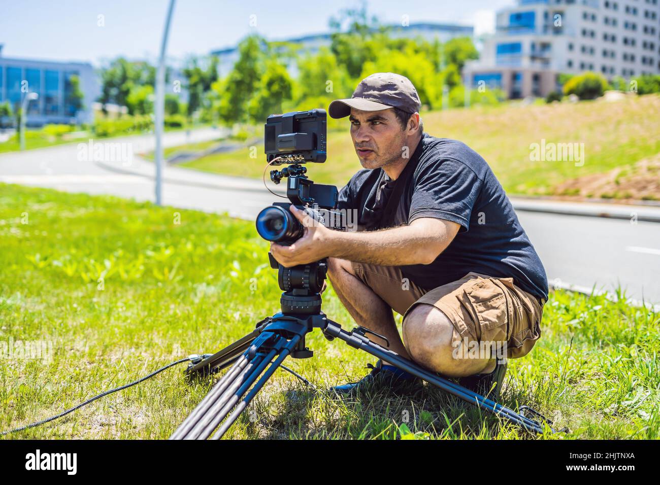 a professional cameraman prepares a camera and a tripod before shooting ...