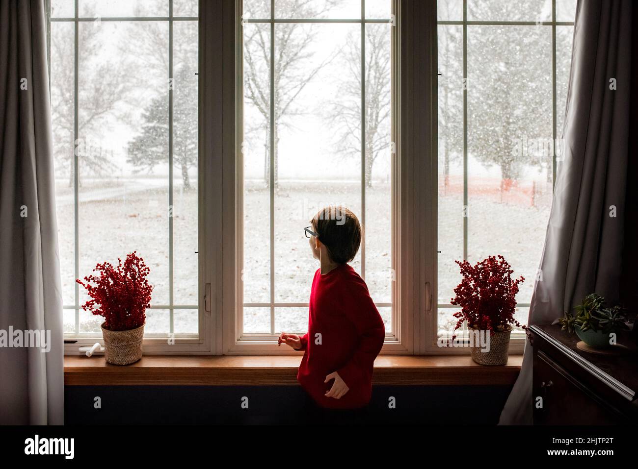 a boy watching the snow fall from his bedroom window Stock Photo - Alamy