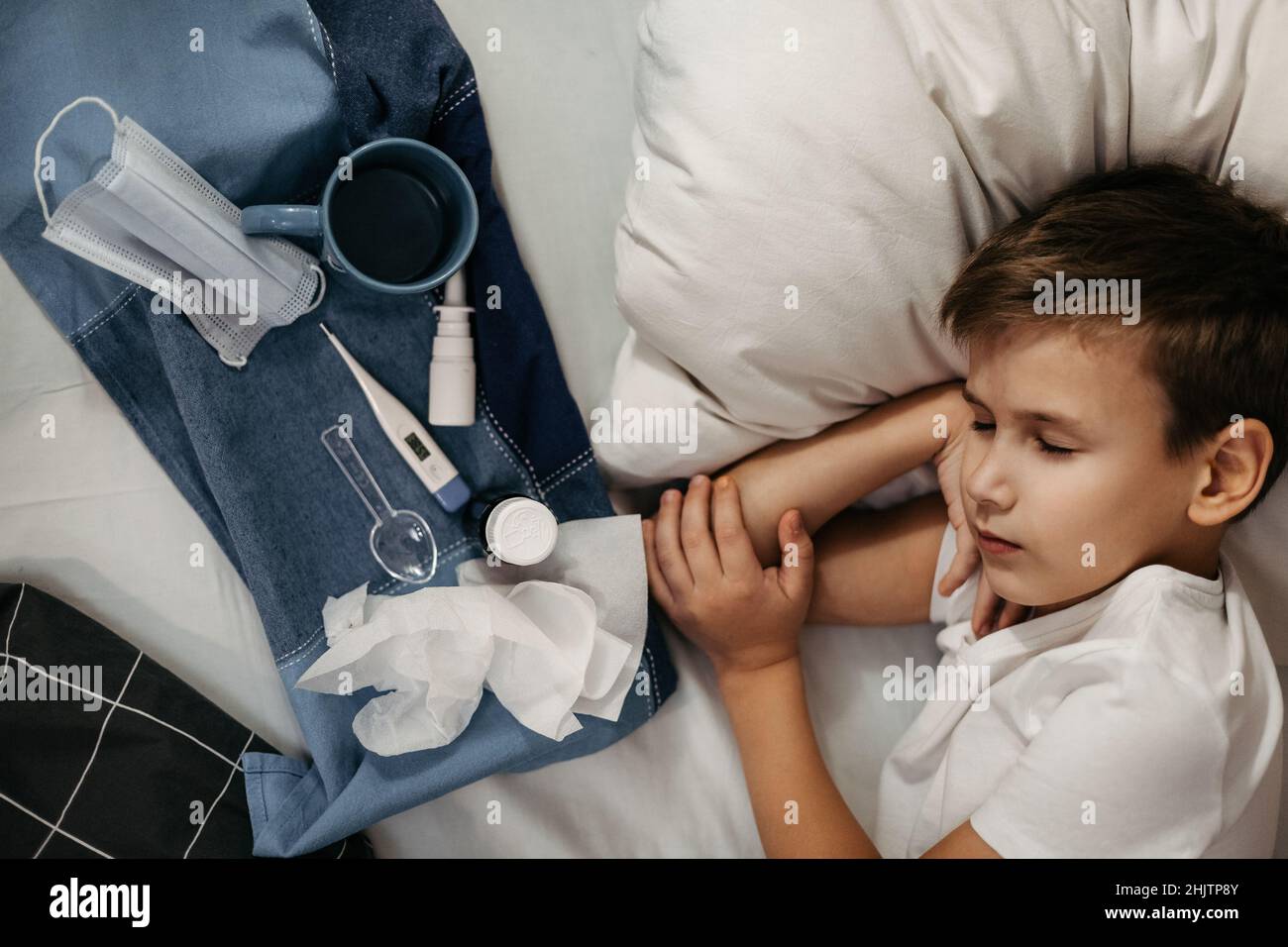 Sick child lying on bed. Some medicines and thermometer lying nearby ...