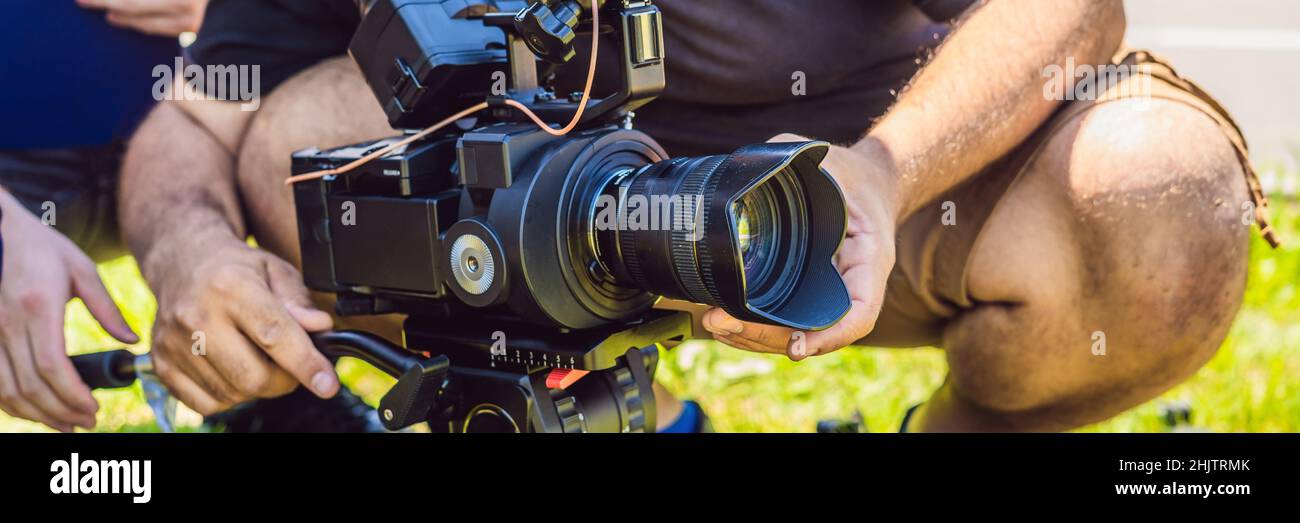 a professional cameraman prepares a camera and a tripod before shooting ...
