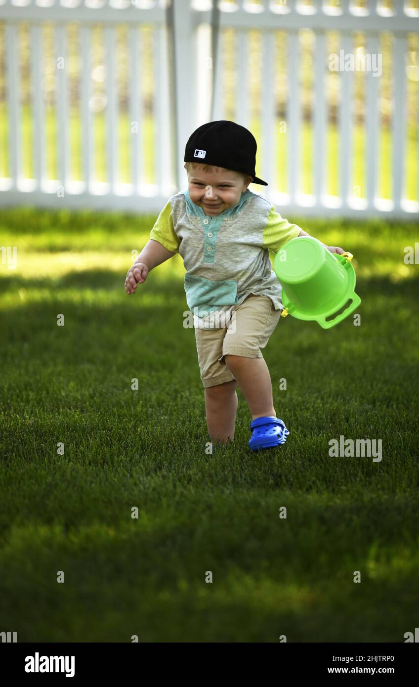 A two-year-old boy running outdoors with a bucket Stock Photo - Alamy