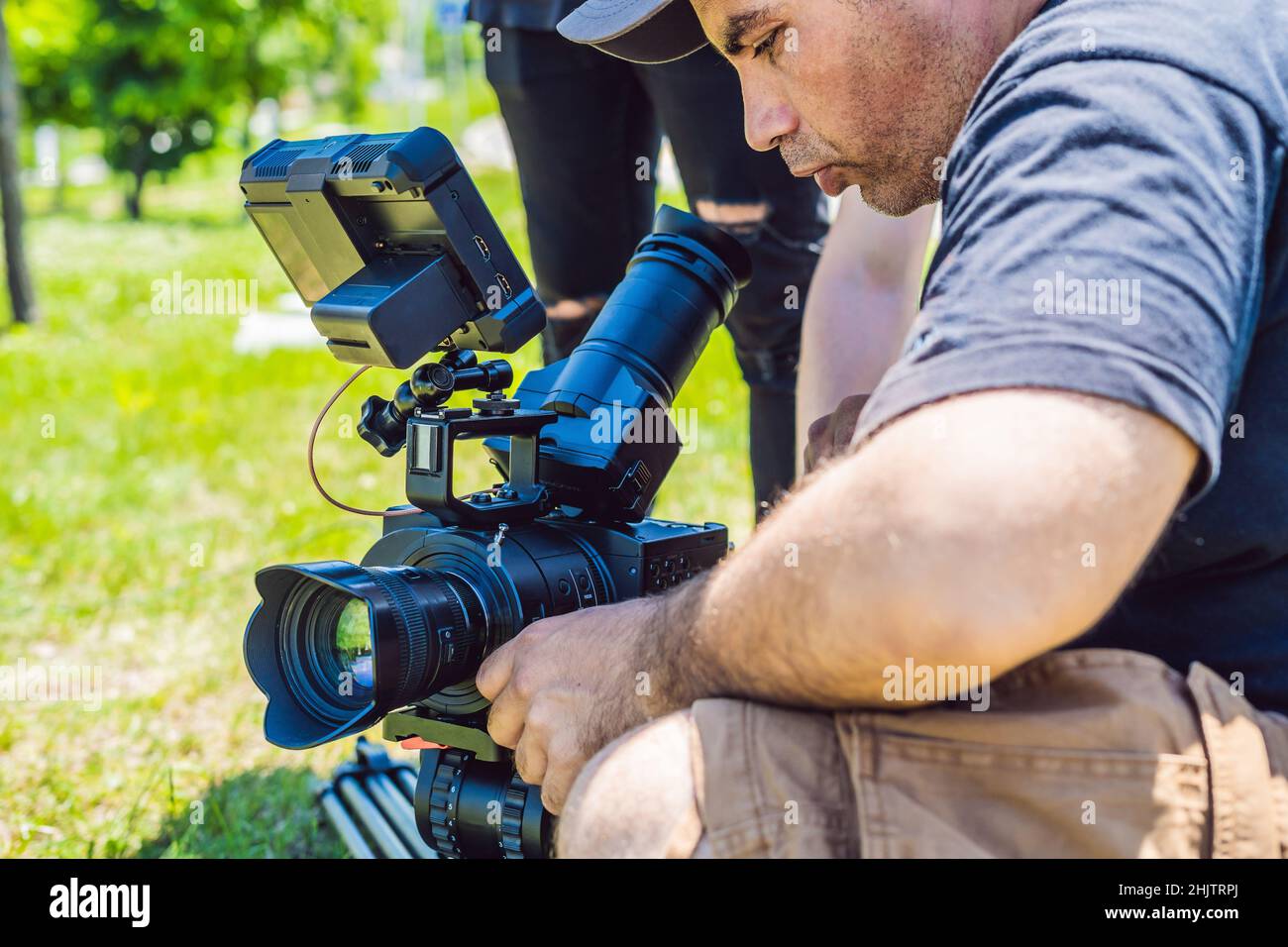 a professional cameraman prepares a camera and a tripod before shooting ...