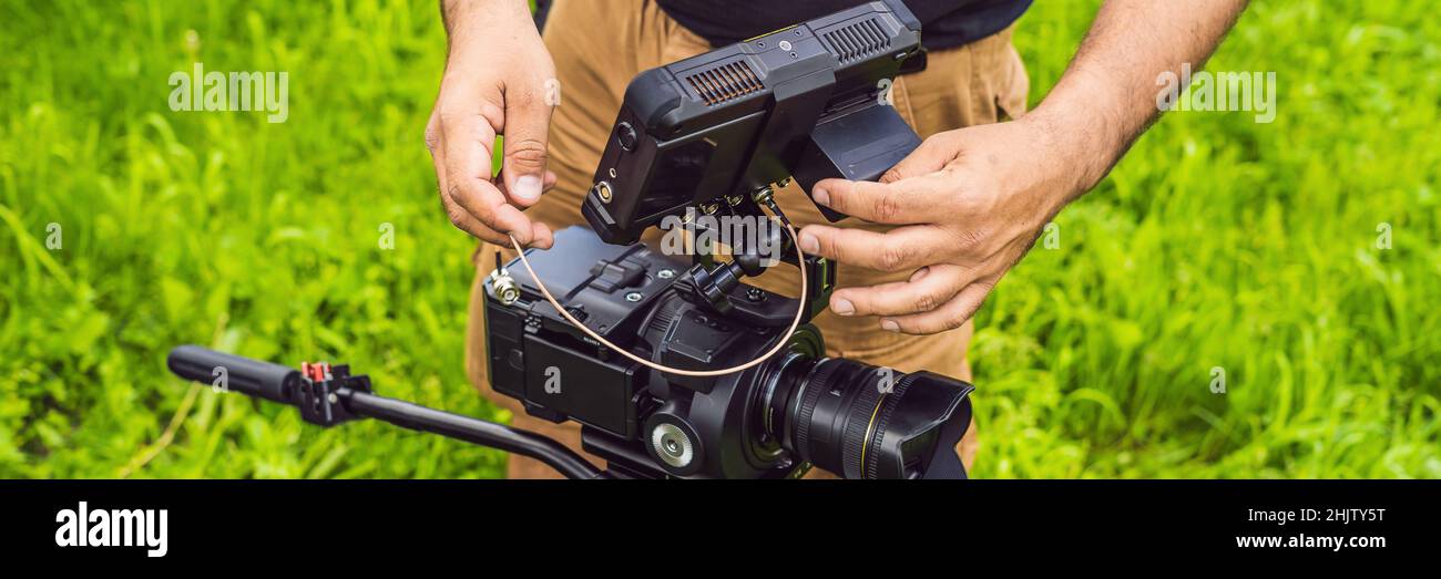 a professional cameraman prepares a camera and a tripod before shooting ...