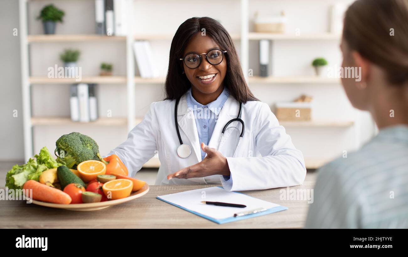 Friendly nutritionist black woman giving consultation to patient and ...