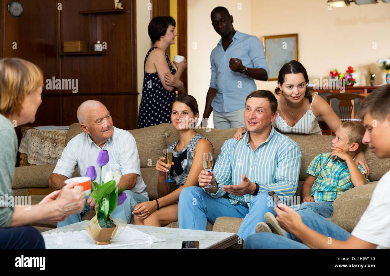 Multigenerational family chatting and drinking wine and tea at home ...