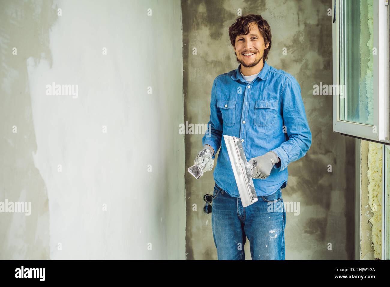 master is applying white putty on a wall and smearing by putty knife in ...
