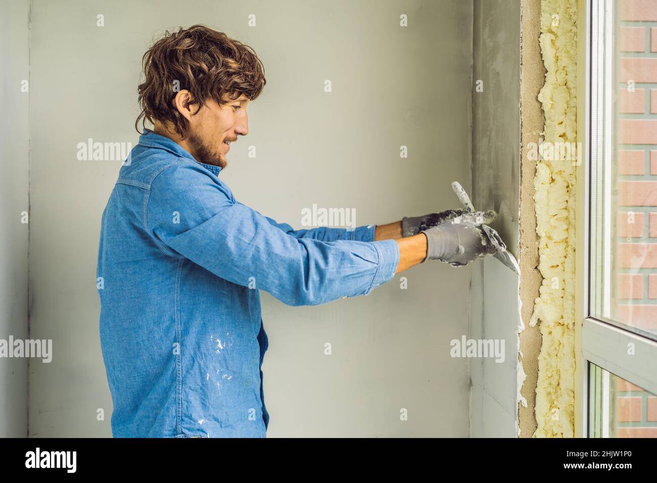 master is applying white putty on a wall and smearing by putty knife in ...