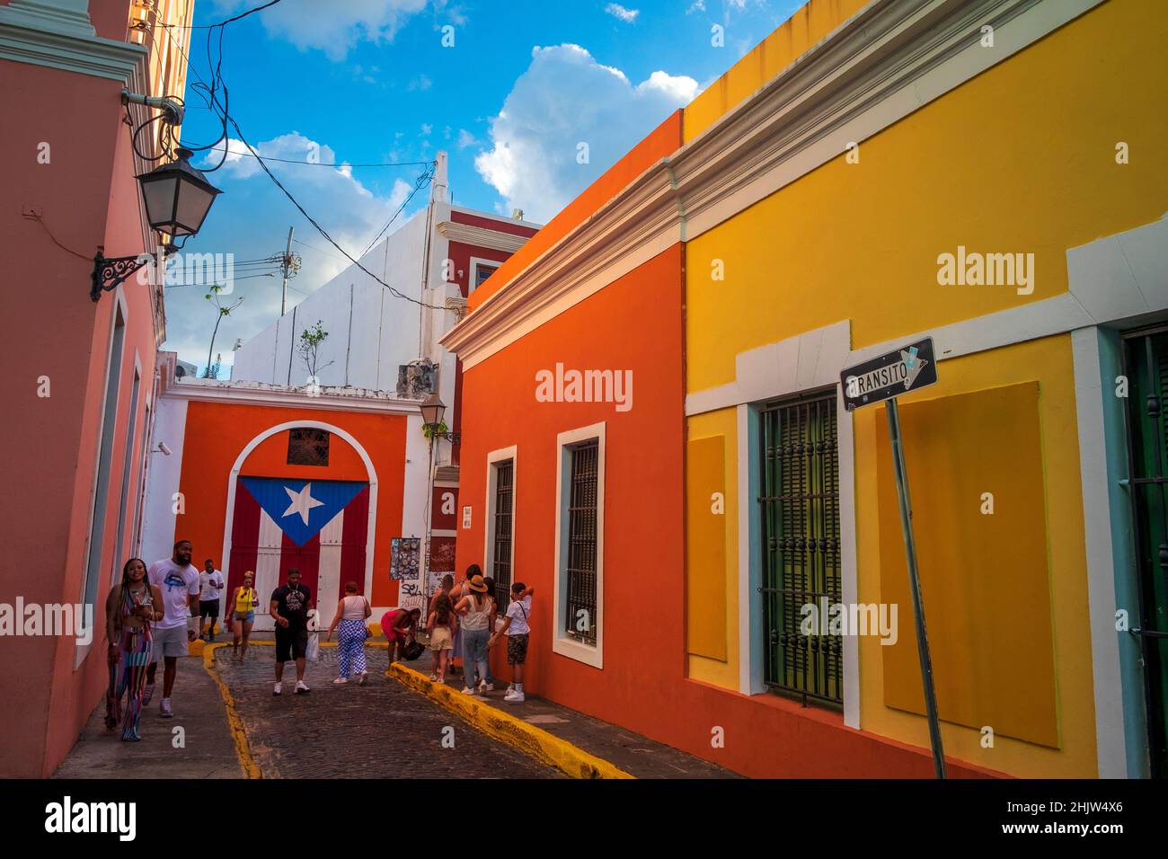 Tourists next to a mural of the Puerto Rican flag in a street full of ...