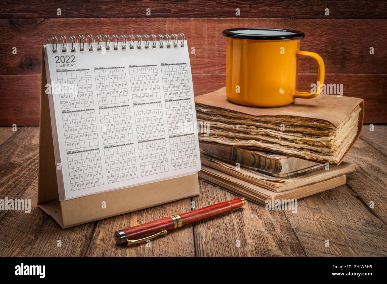 2022 year - spiral desktop calendar with old books against rustic wood ...