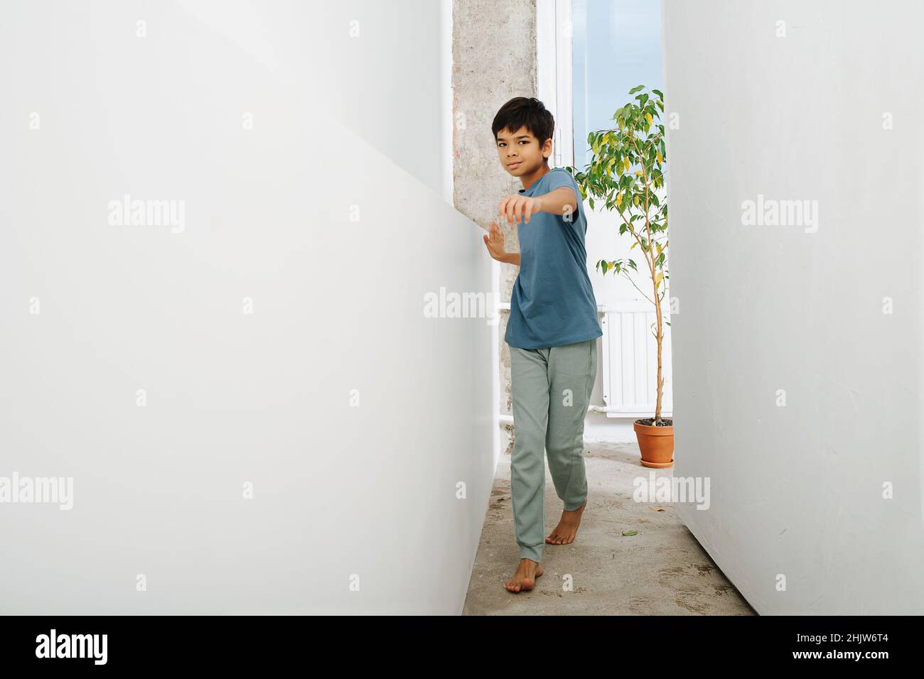Handsome indian boy walking in a corridor between a wall and a set ...