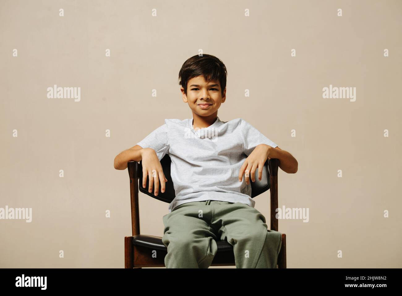 Ordinary indian boy sitting on an armchair in a room over beige ...