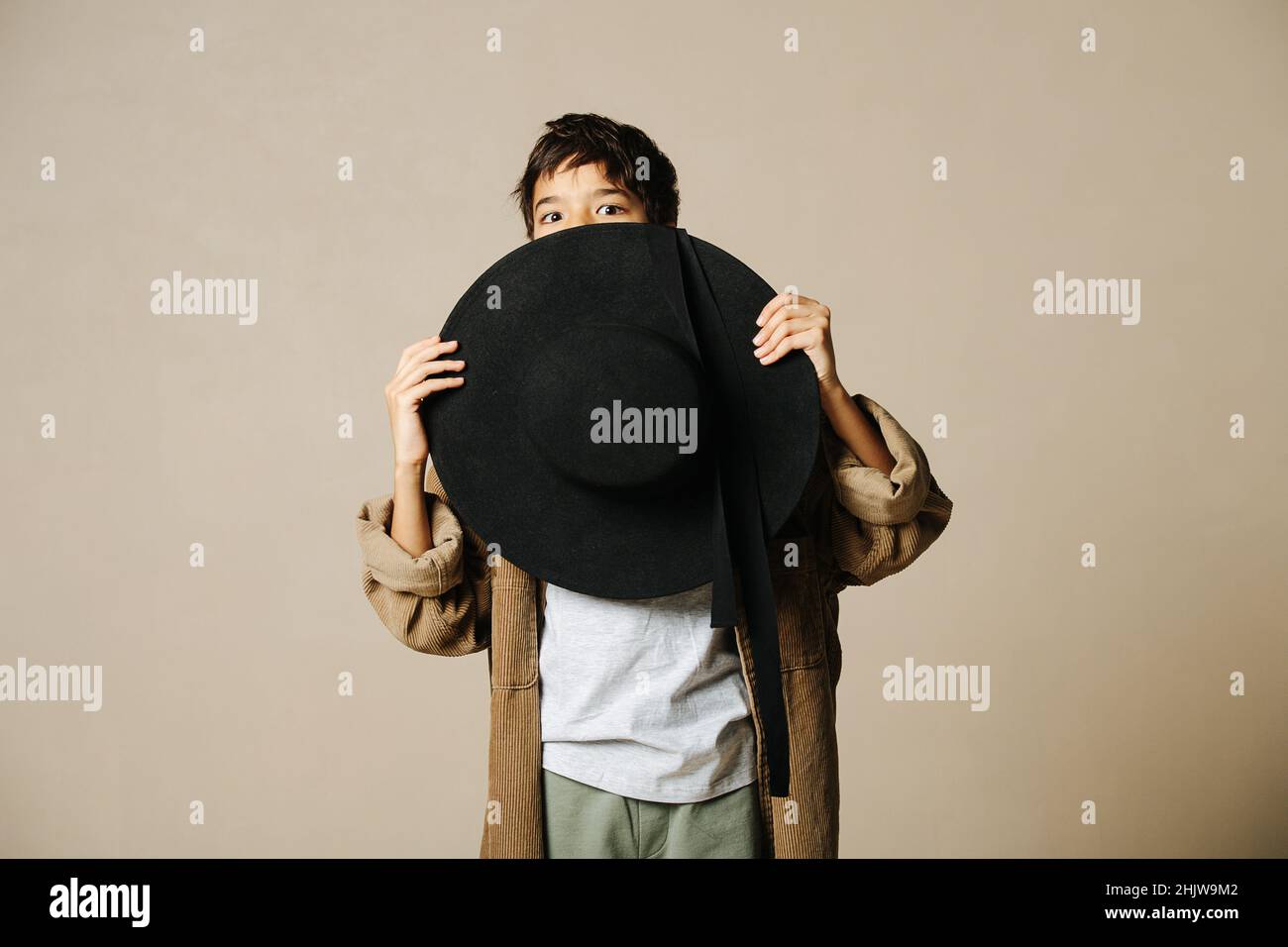 Funny spooked indian boy in oversize long sleeve shirt hiding behind ...