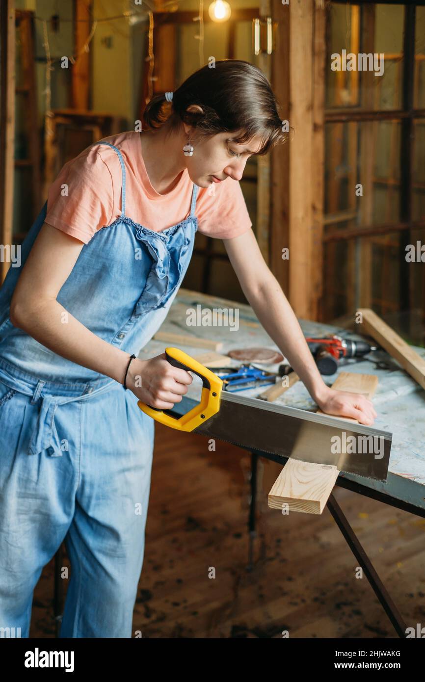 Woman working with wood in workshop. Measuring plunk, drilling holes ...