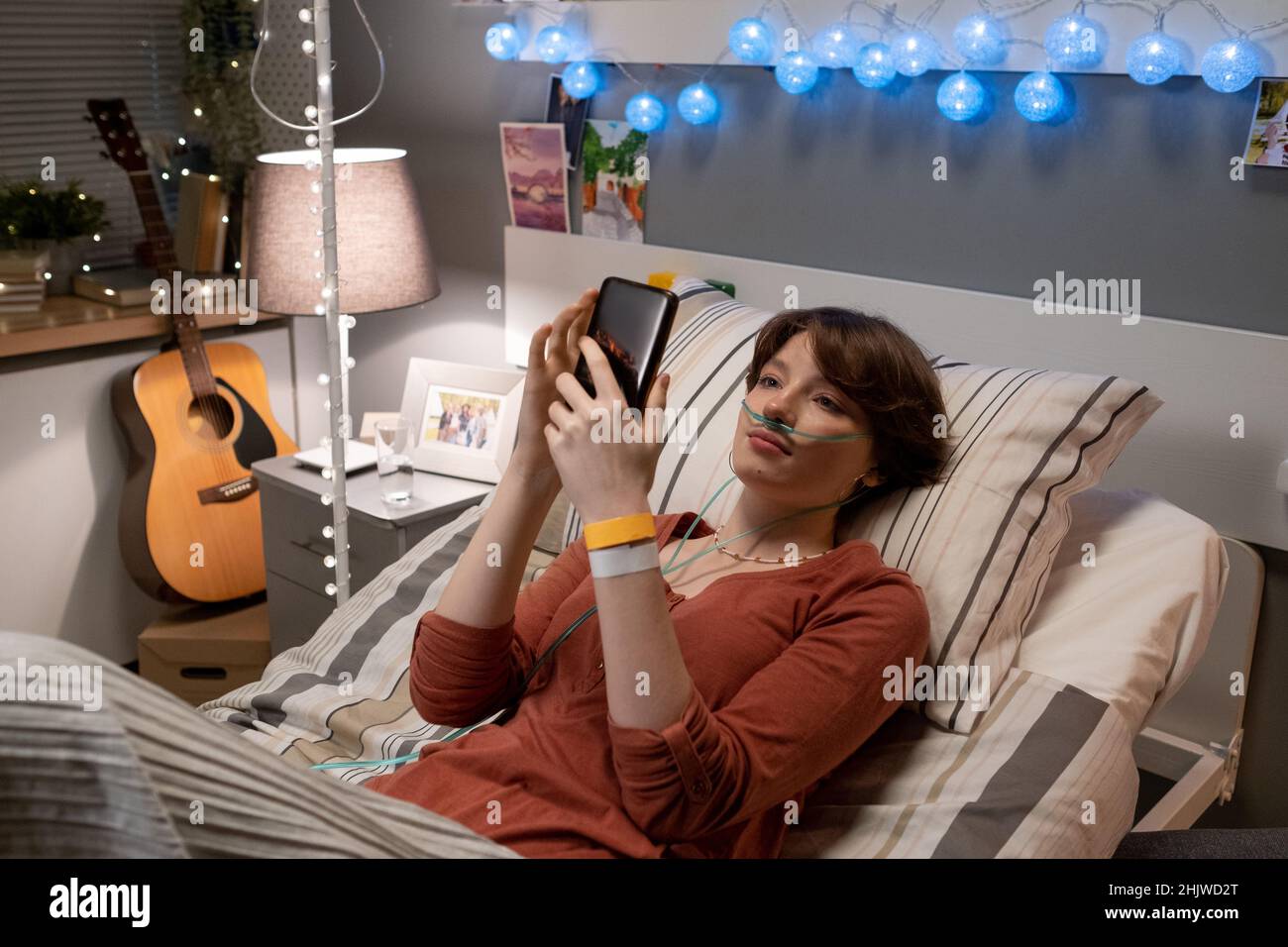 Sick teenage girl using her mobile phone before sleep while lying on ...