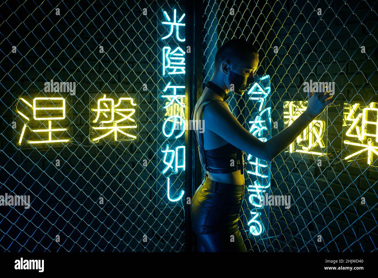 Cyborg girl in black leather clothes standing behind bars in dark ...