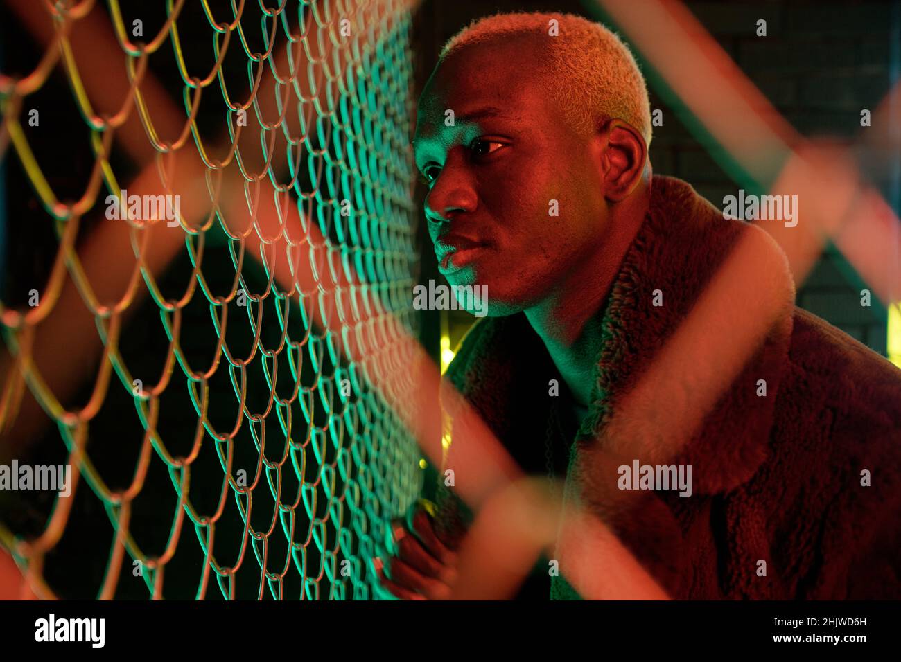 Young sad and lonely African man in brown furcoat standing close to ...