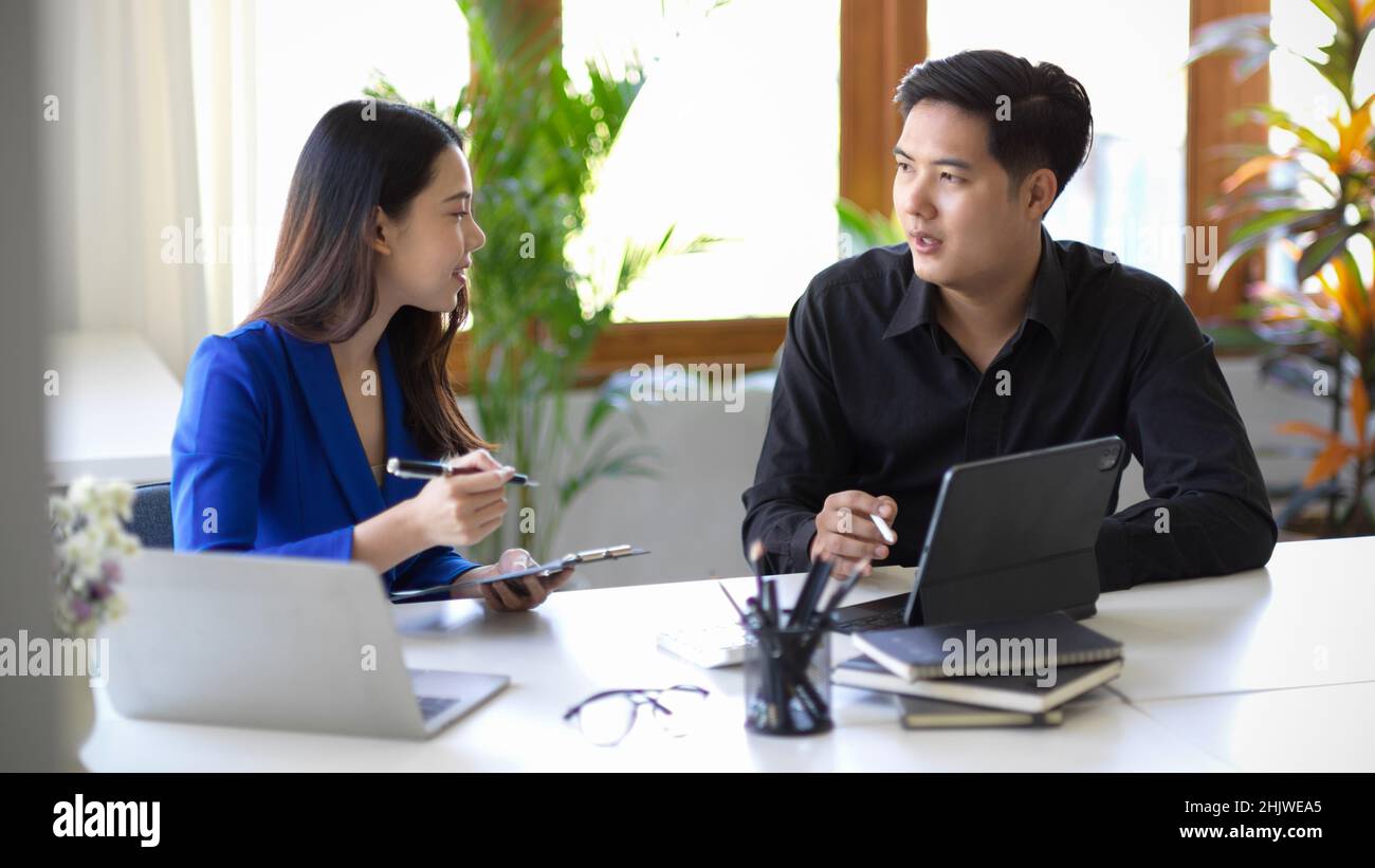 Two asian colleagues worker having a small talk, discuss their work ...