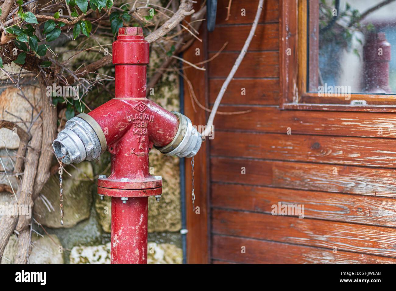 Close-up - overhead red pressurized fire hydrant against wooden house ...