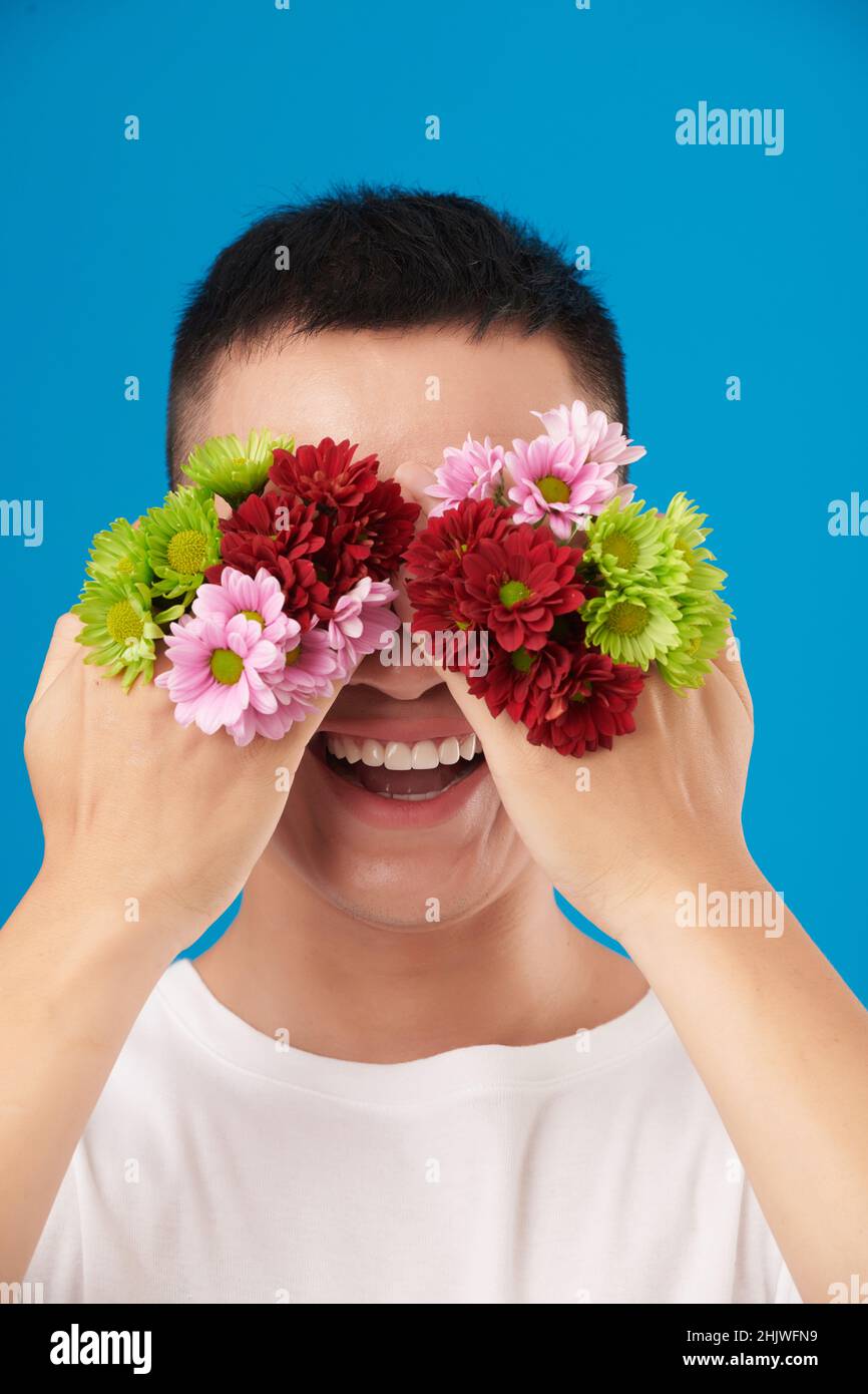 Portrait of happy excited young man holding beautiful blooming flowers ...