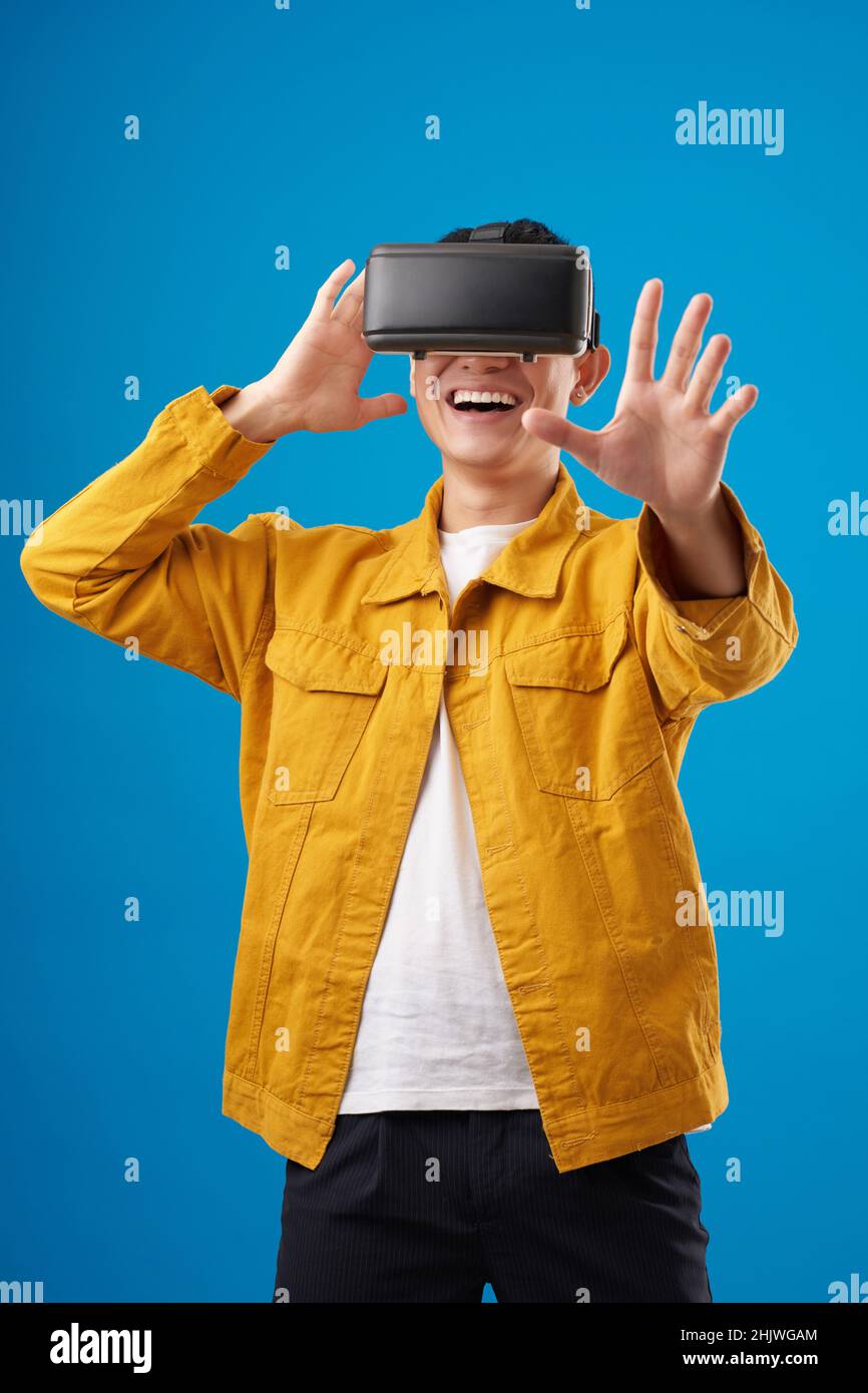 Happy millennial man in vr glasses playing and trying to touch ...