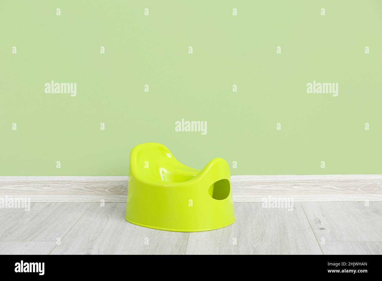 Potty on grey wooden floor near green wall Stock Photo - Alamy