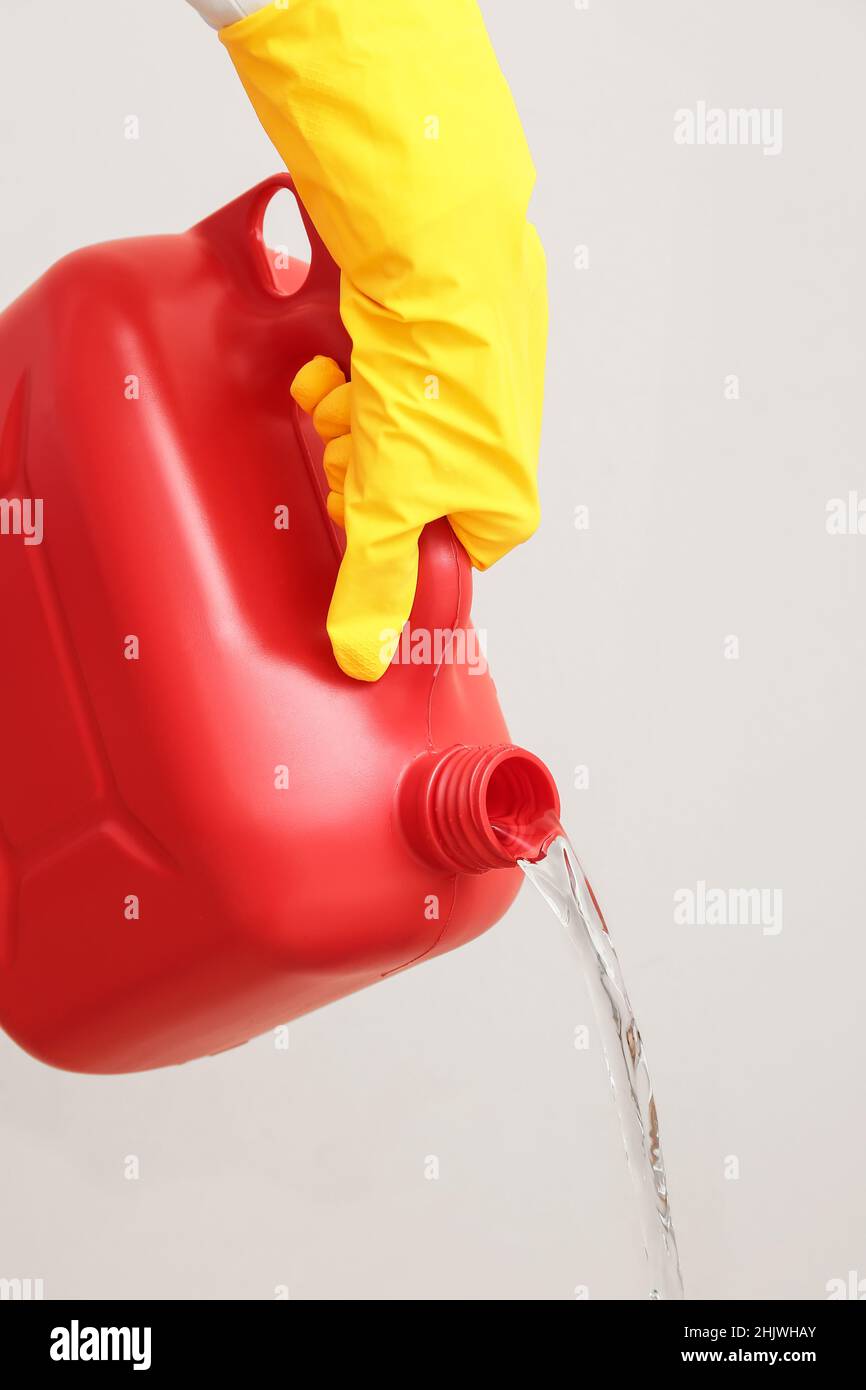 Man pouring out liquid from plastic canister on light background Stock ...