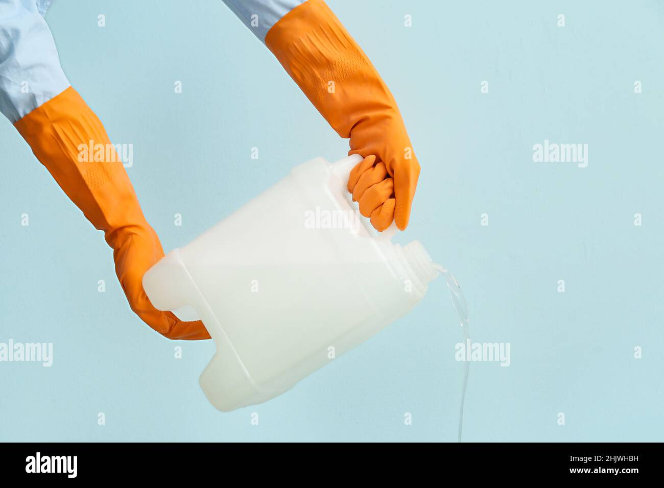 Man pouring out liquid from plastic canister on color background Stock ...