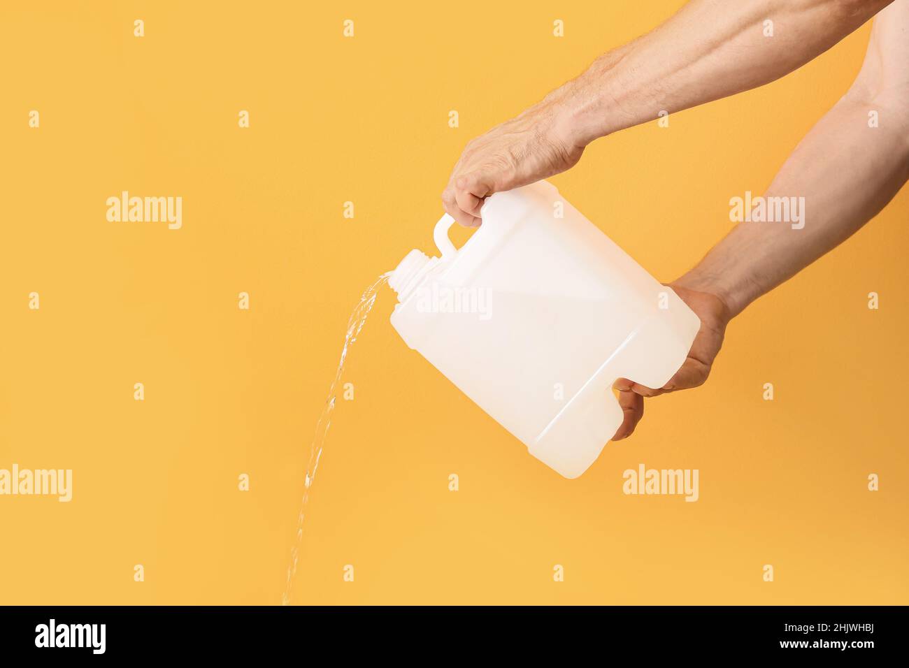 Man pouring out liquid from plastic canister on color background Stock ...
