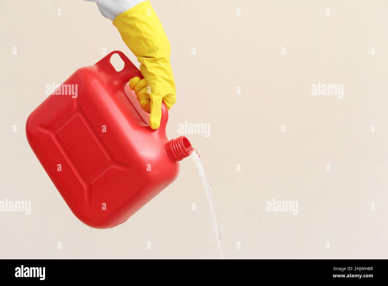 Man pouring out liquid from plastic canister on light background Stock ...