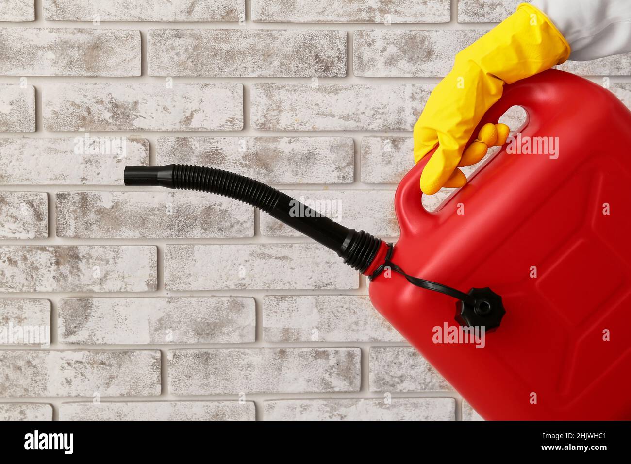 Male hand in rubber gloves holding canister near brick wall Stock Photo ...