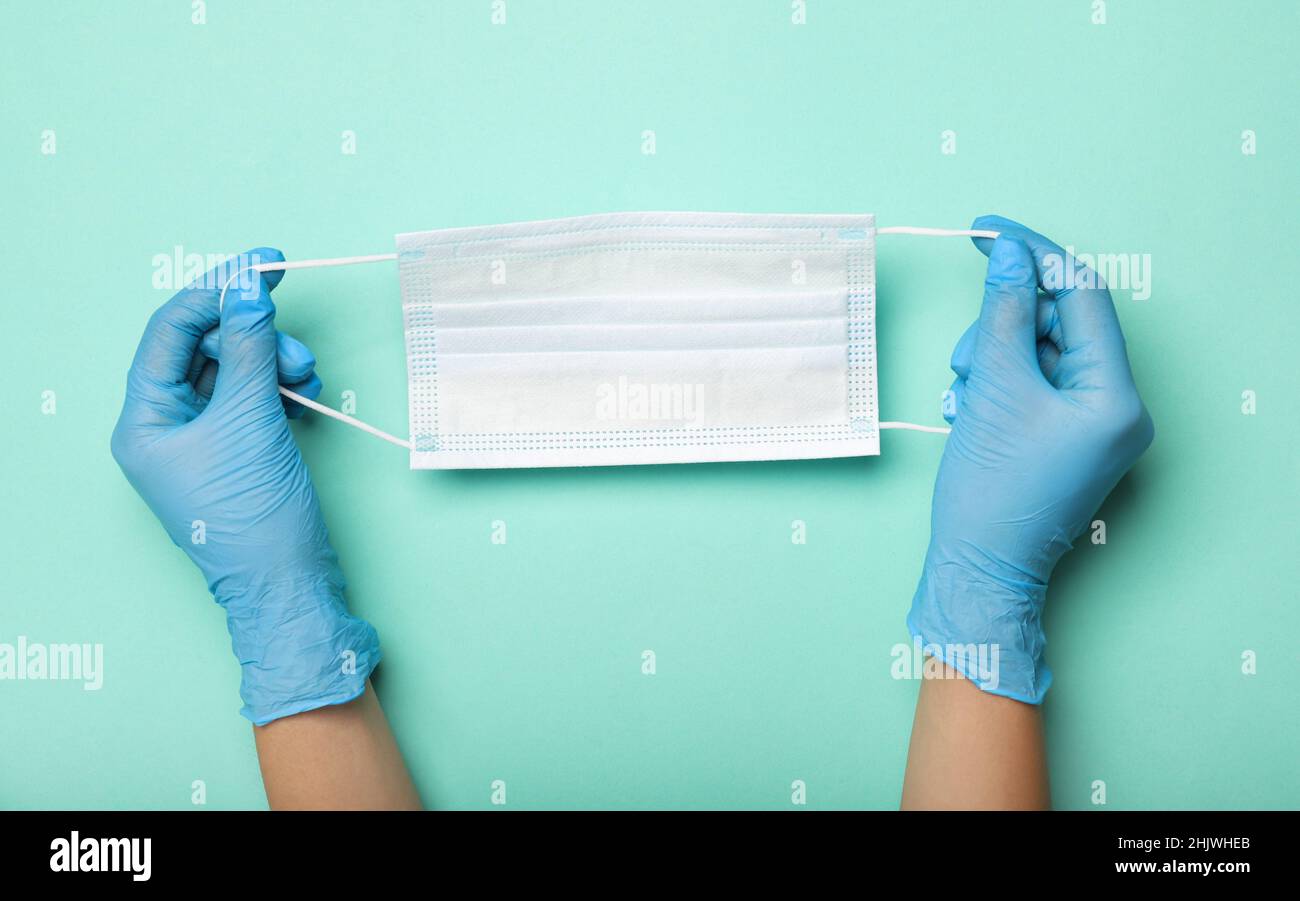 Female hands in rubber gloves with medical mask on color background ...
