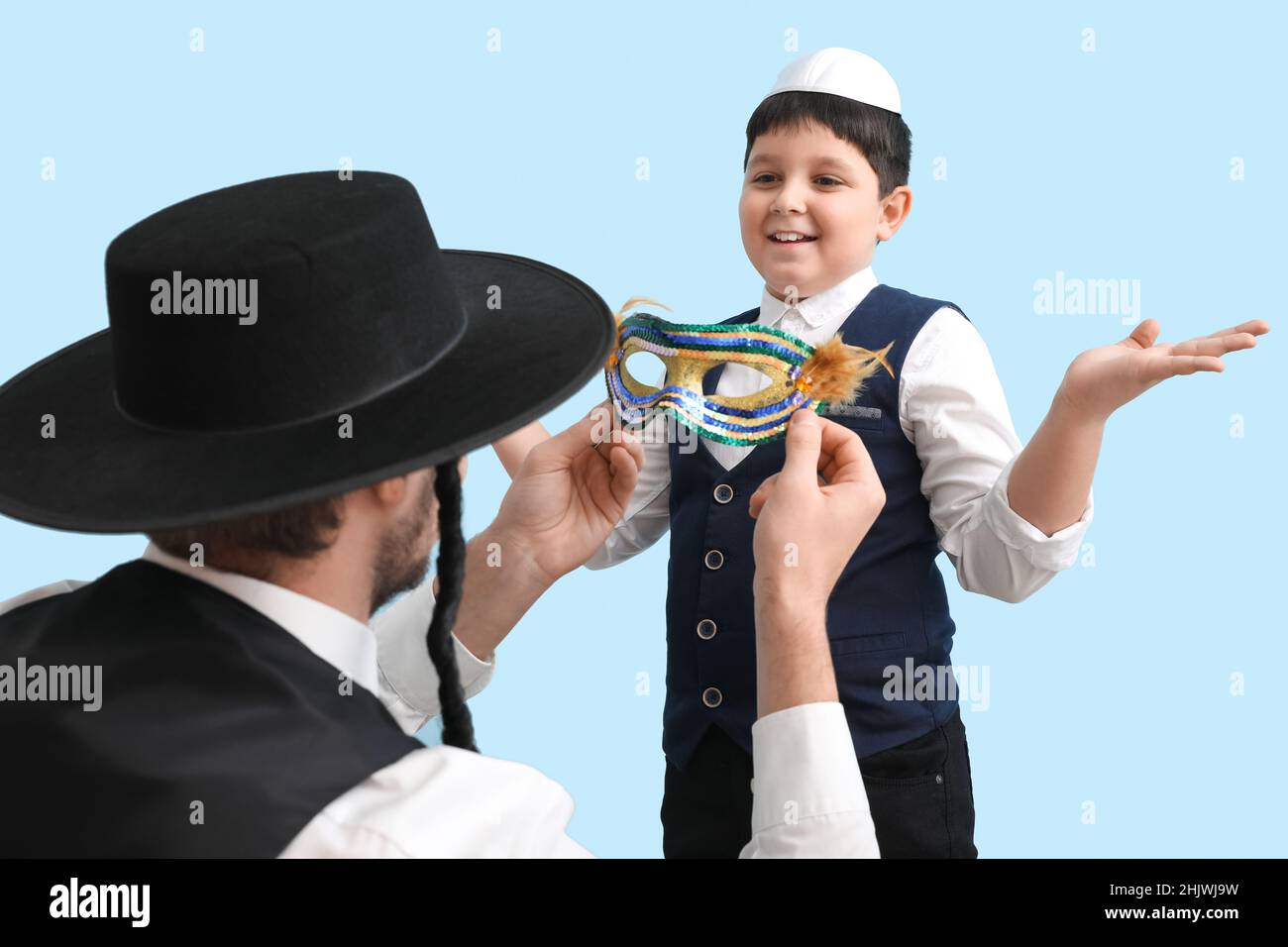 Jewish man and boy with carnival mask for Purim holiday on color ...