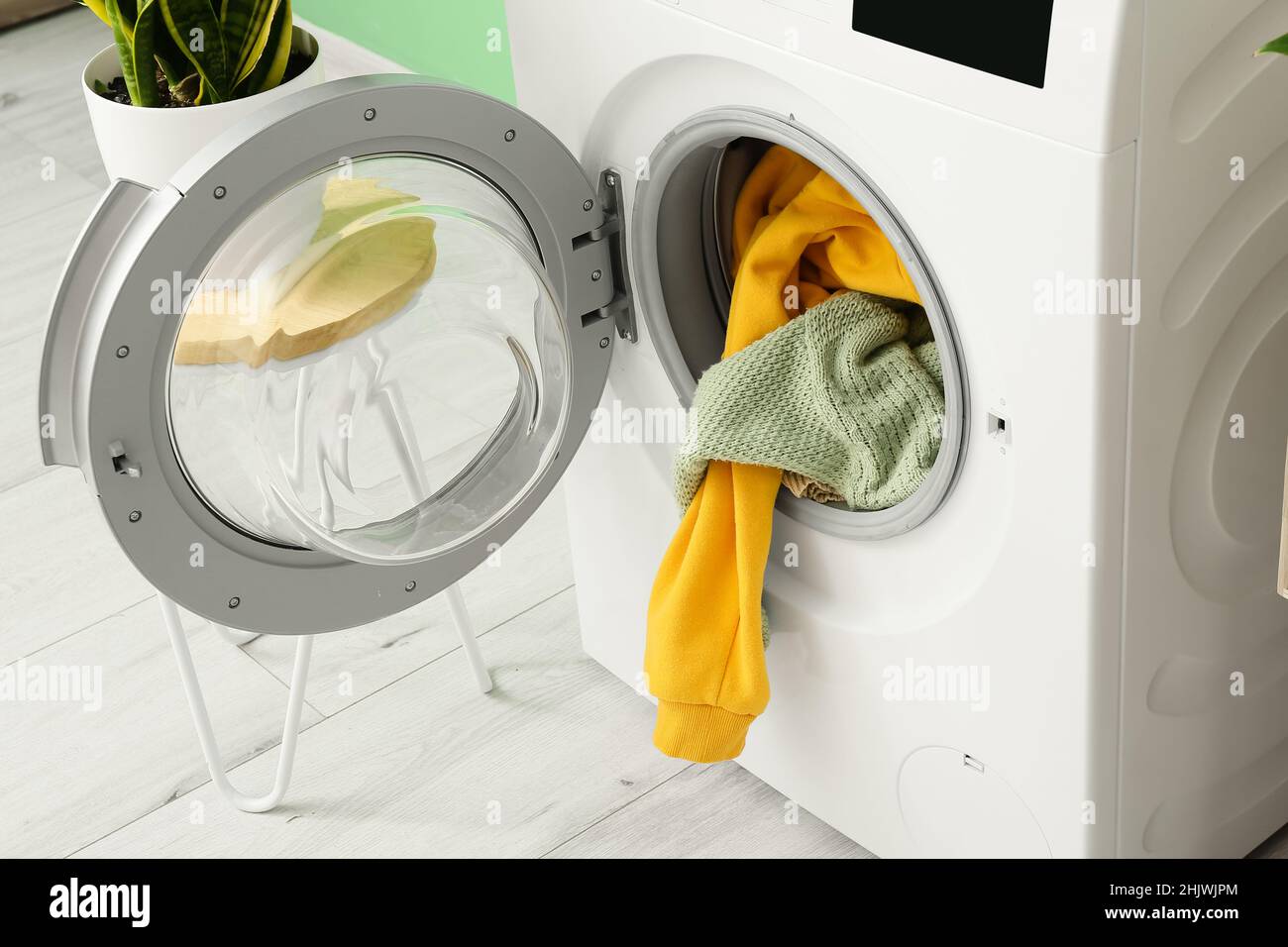 Modern washing machine with dirty clothes and table Stock Photo - Alamy